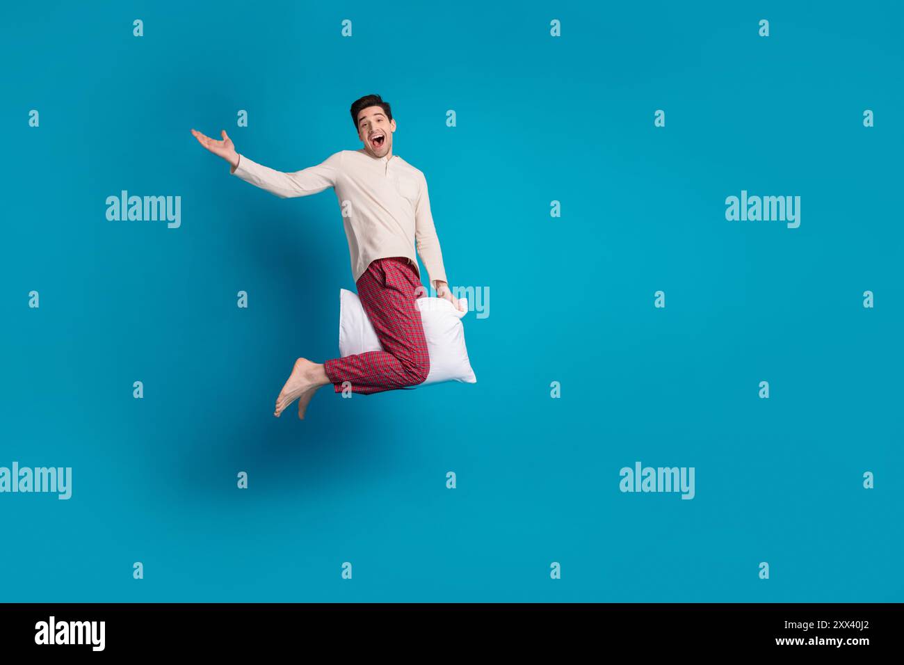 Full length photo of handsome young guy riding pillow excited dressed ...