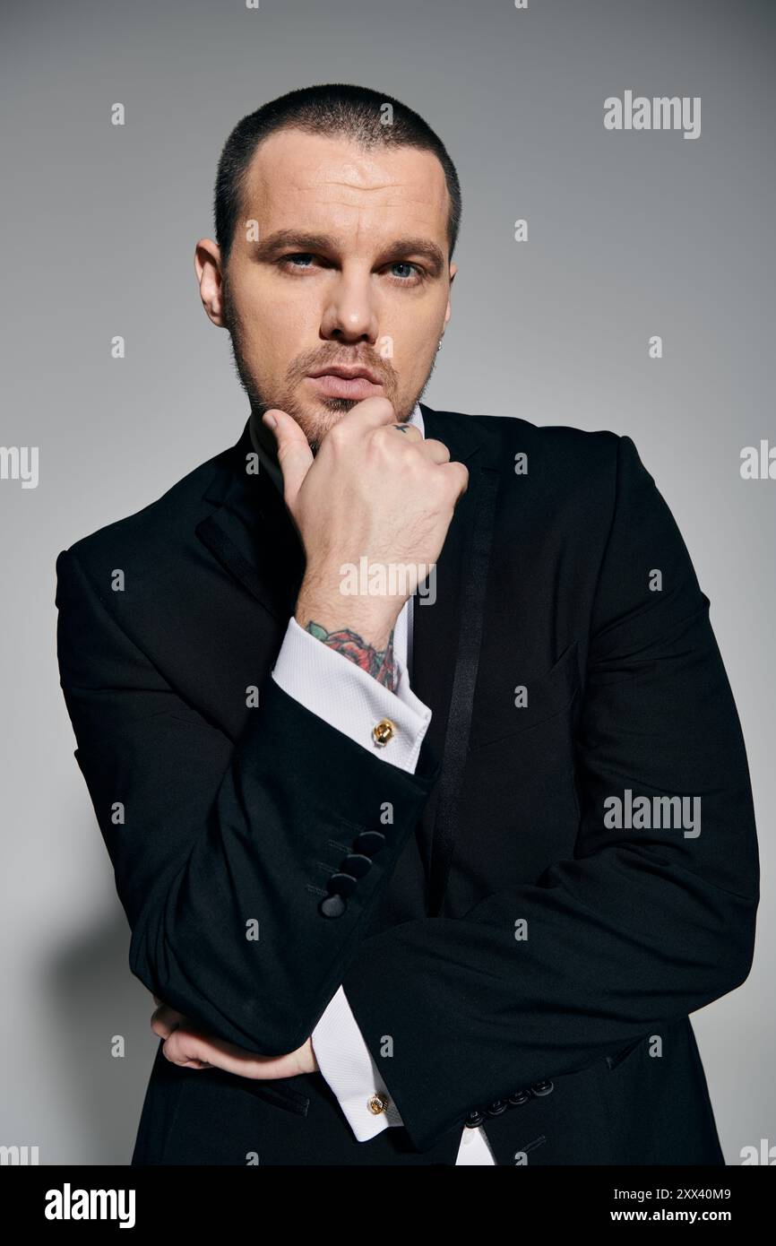 A man in a sharp black suit with a white shirt stares thoughtfully into ...