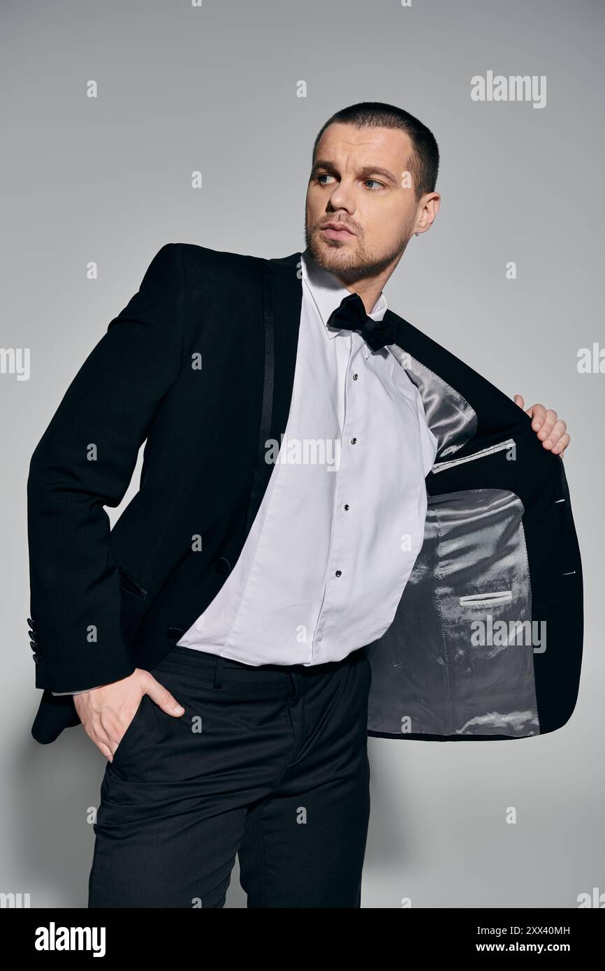 A man in a black suit adjusts his jacket, showing off the lining Stock ...