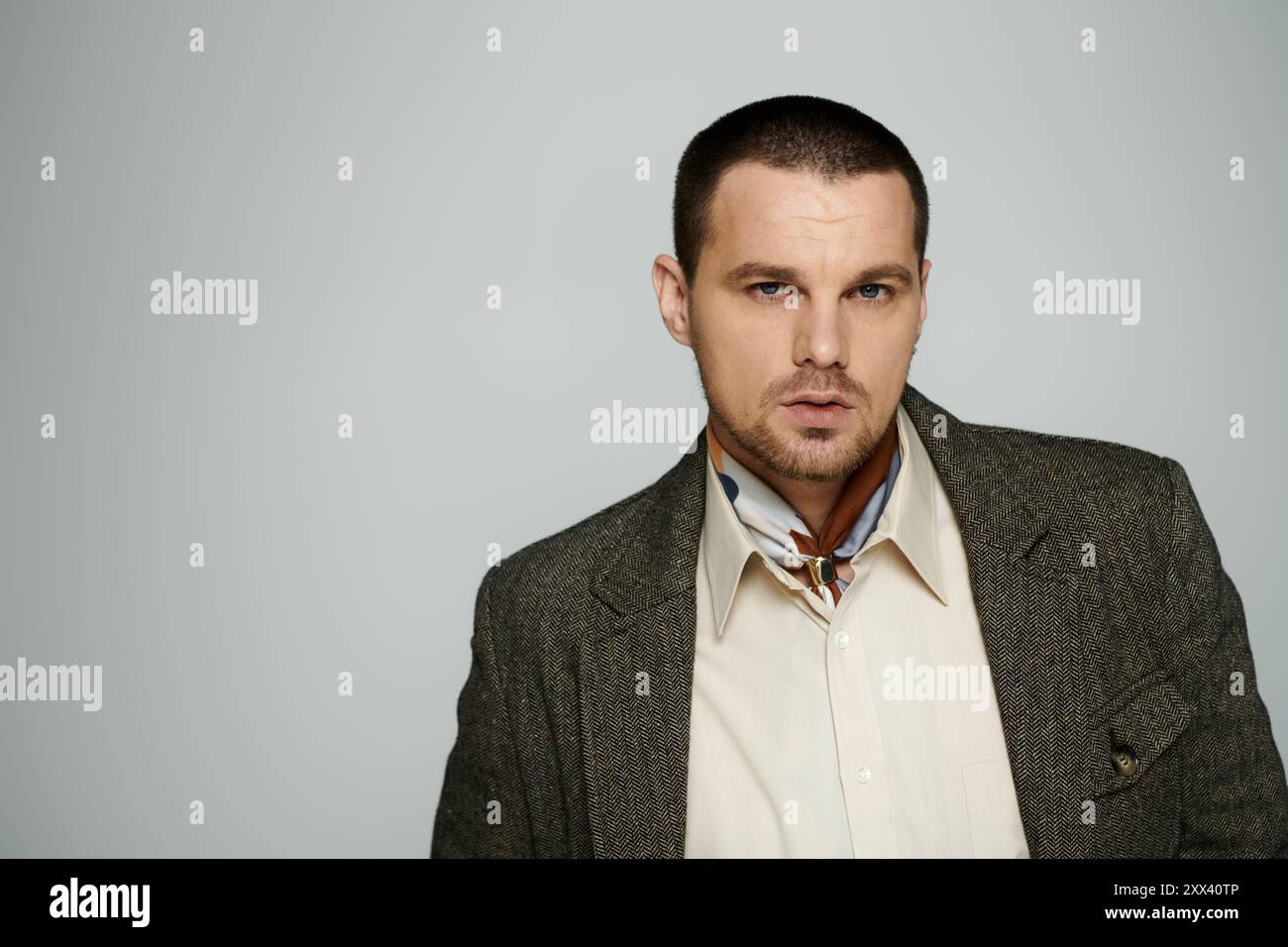 Man in tweed jacket, white shirt, patterned scarf looks at camera Stock ...