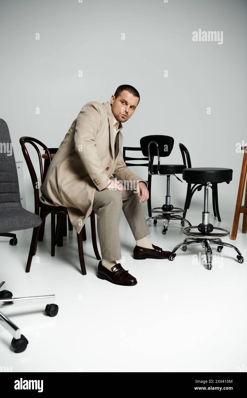 A stylish man sits on a chair, surrounded by other chairs in a studio ...