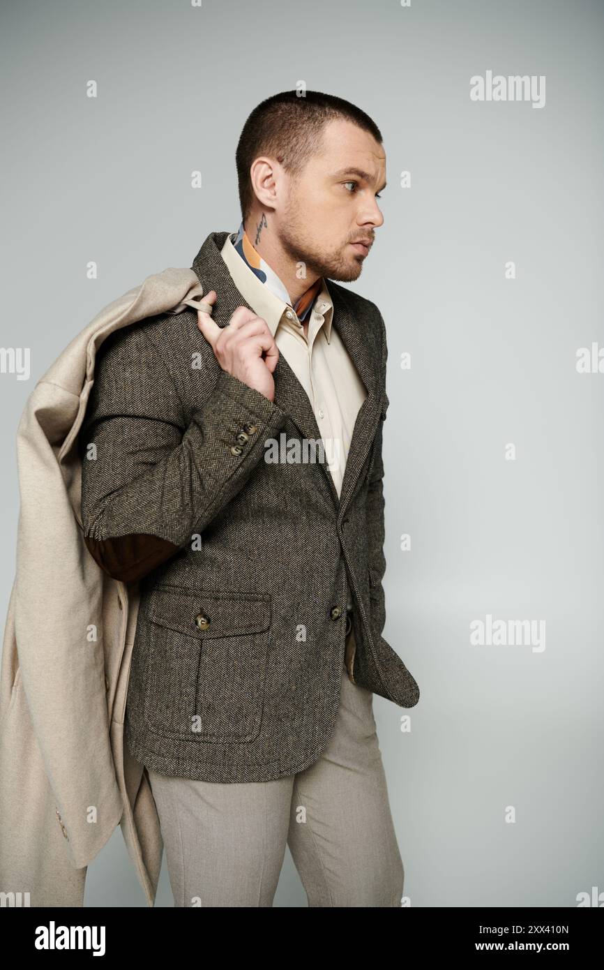 A man in a tweed jacket and light trousers poses confidently against a ...
