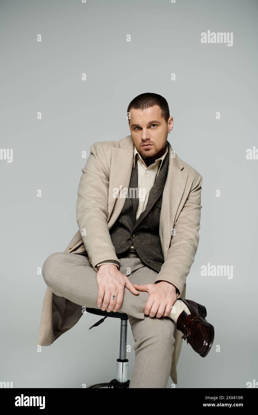 A man in a beige coat sits on a stool, his legs crossed Stock Photo - Alamy
