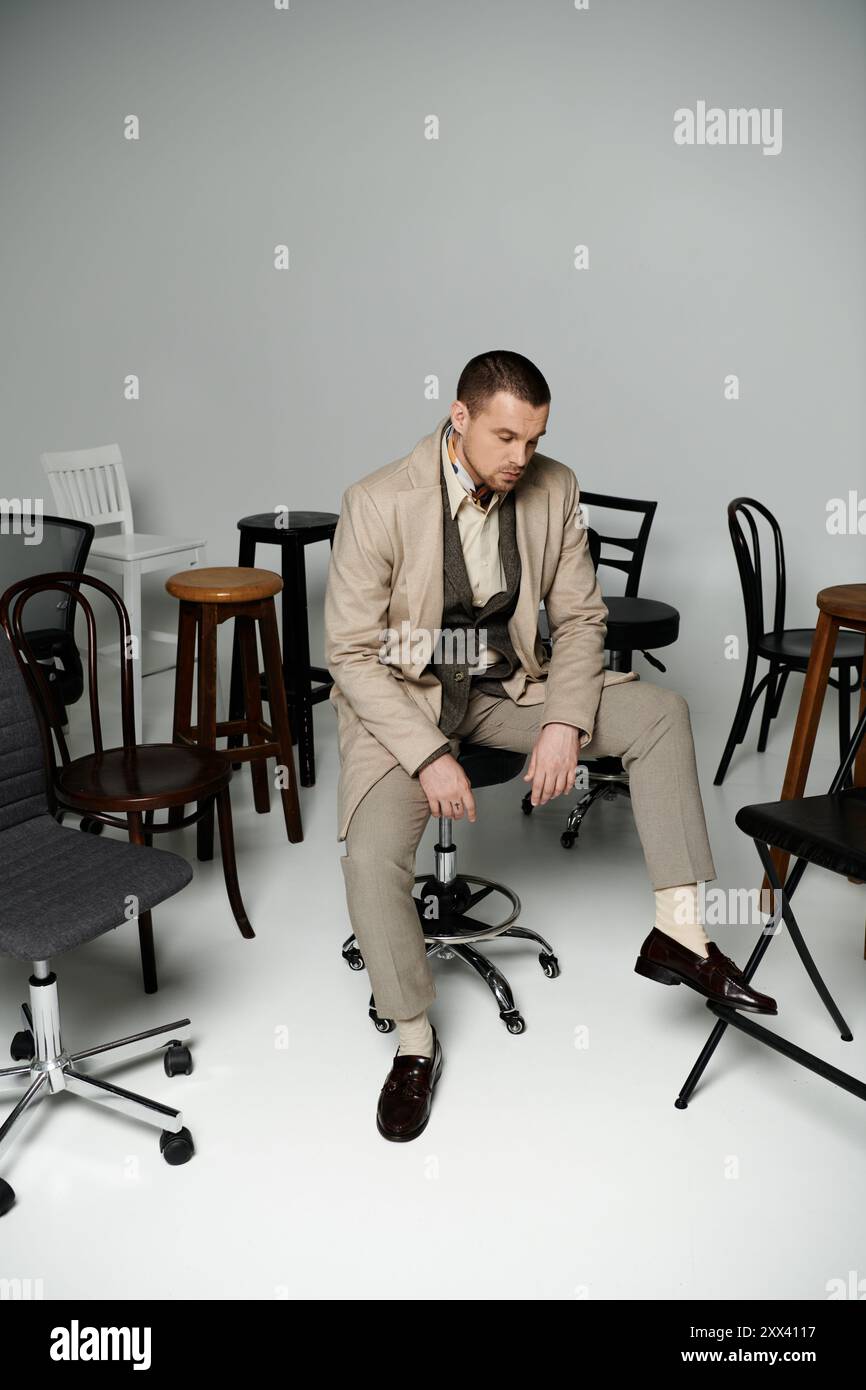 A man in a beige suit sits on a swivel chair surrounded by other chairs ...