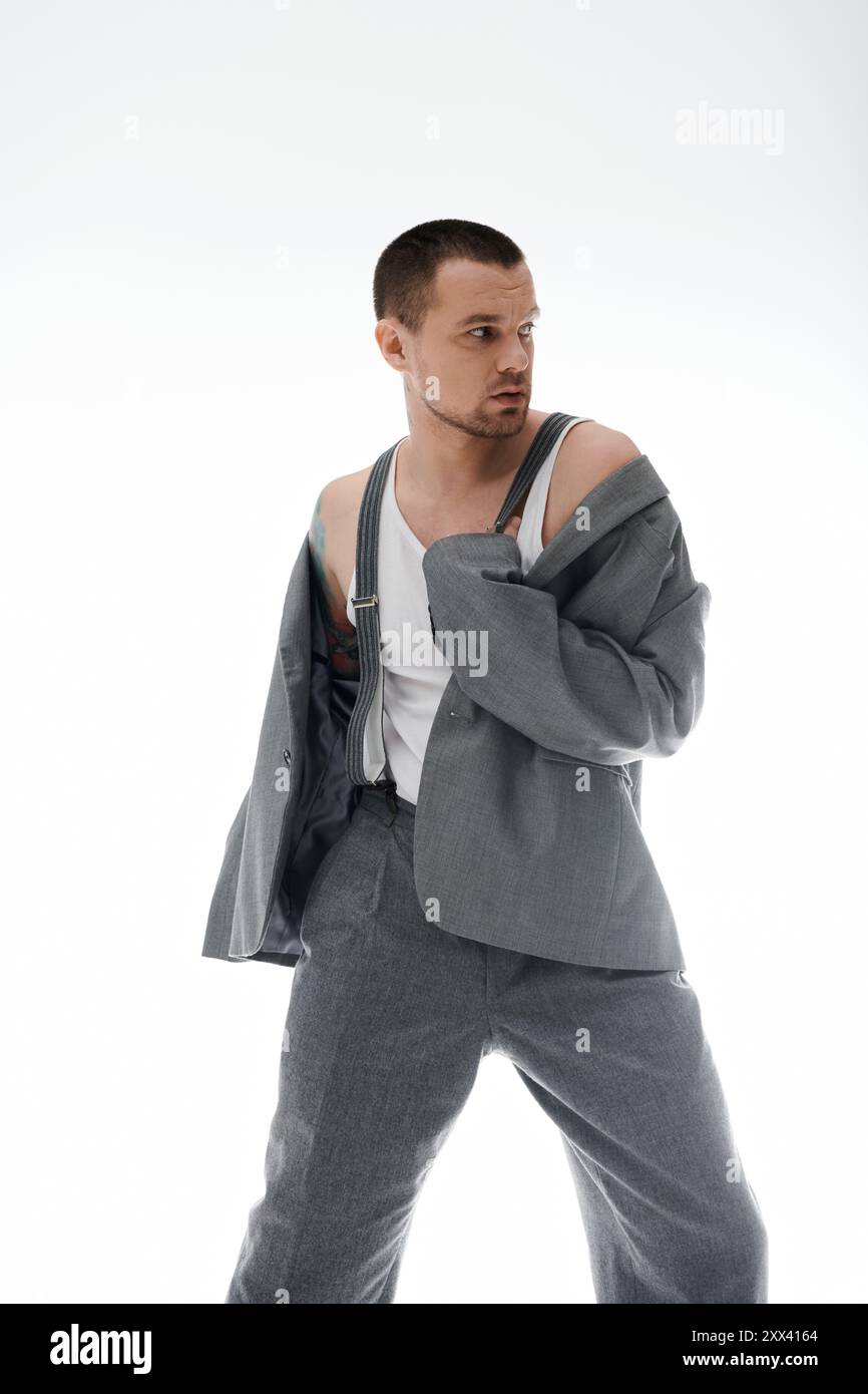 A man in a grey suit jacket and trousers, with suspenders, looks back ...