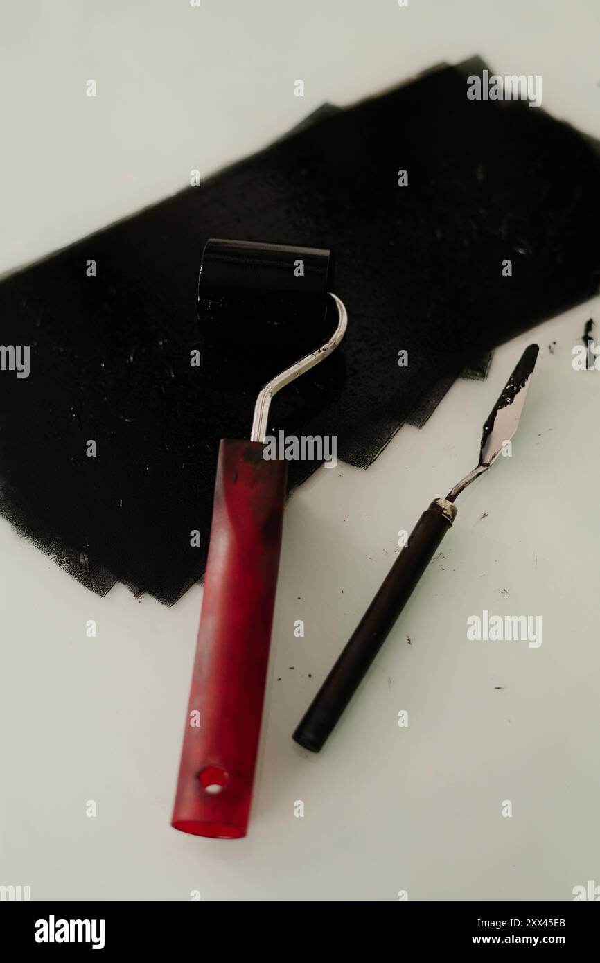 Overview of paintroller with red plastic handle lying on stack of black ...