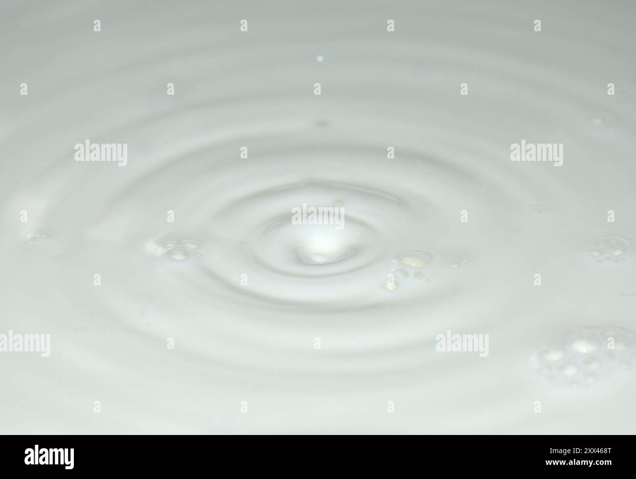 drop of white fresh milk falling to surface splashing and making wave ...