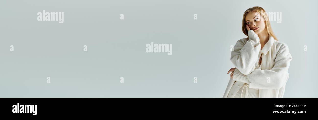 A young woman in a white cardigan poses against a light blue backdrop ...