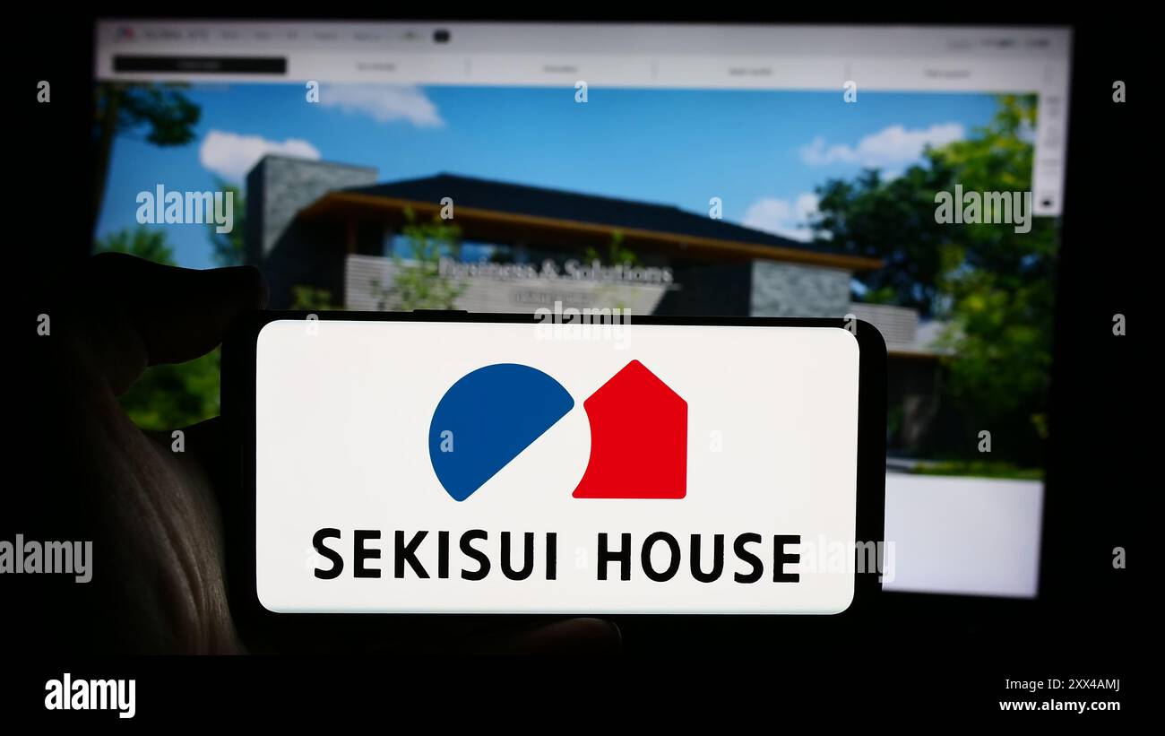 Person holding cellphone with logo of Japanese homebuilding company ...