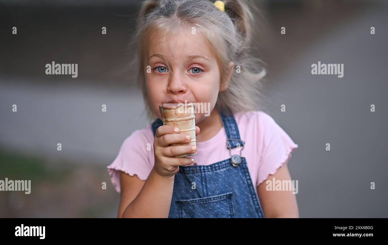 Portrait of a child in summer clothes eating ice cream on a hot day. A ...