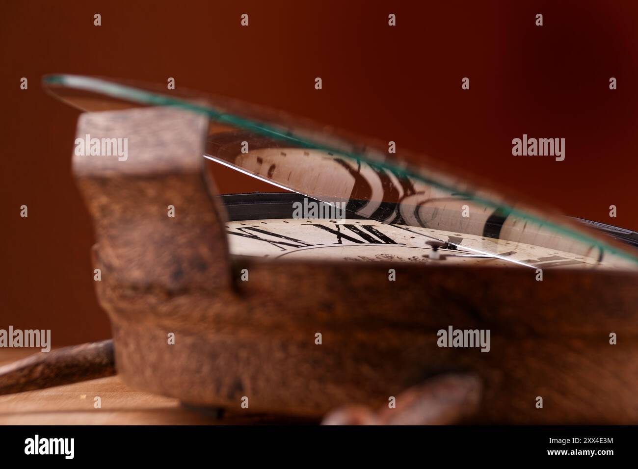 Broken old analog clock with glass and metal frame on wooden table ...