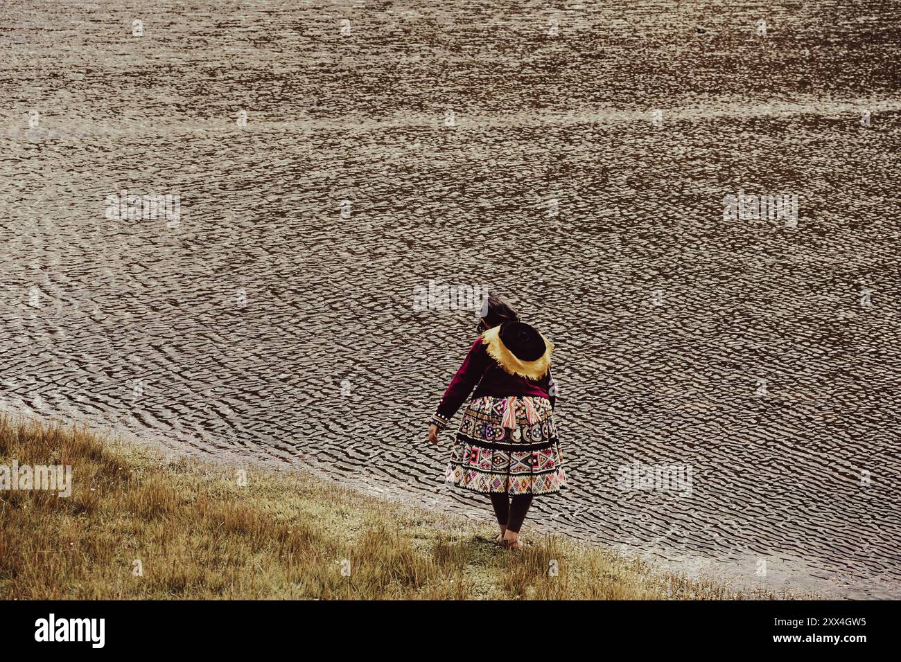Quechua woman in traditional clothes walking by a Lake in the Andes ...
