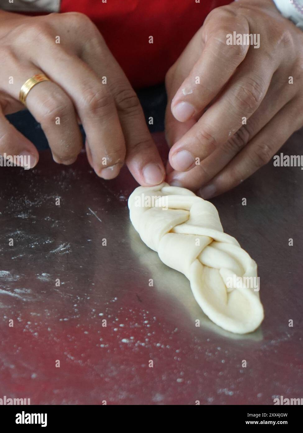 Hand shaping the dough by braiding it. Bread making process Stock Photo ...