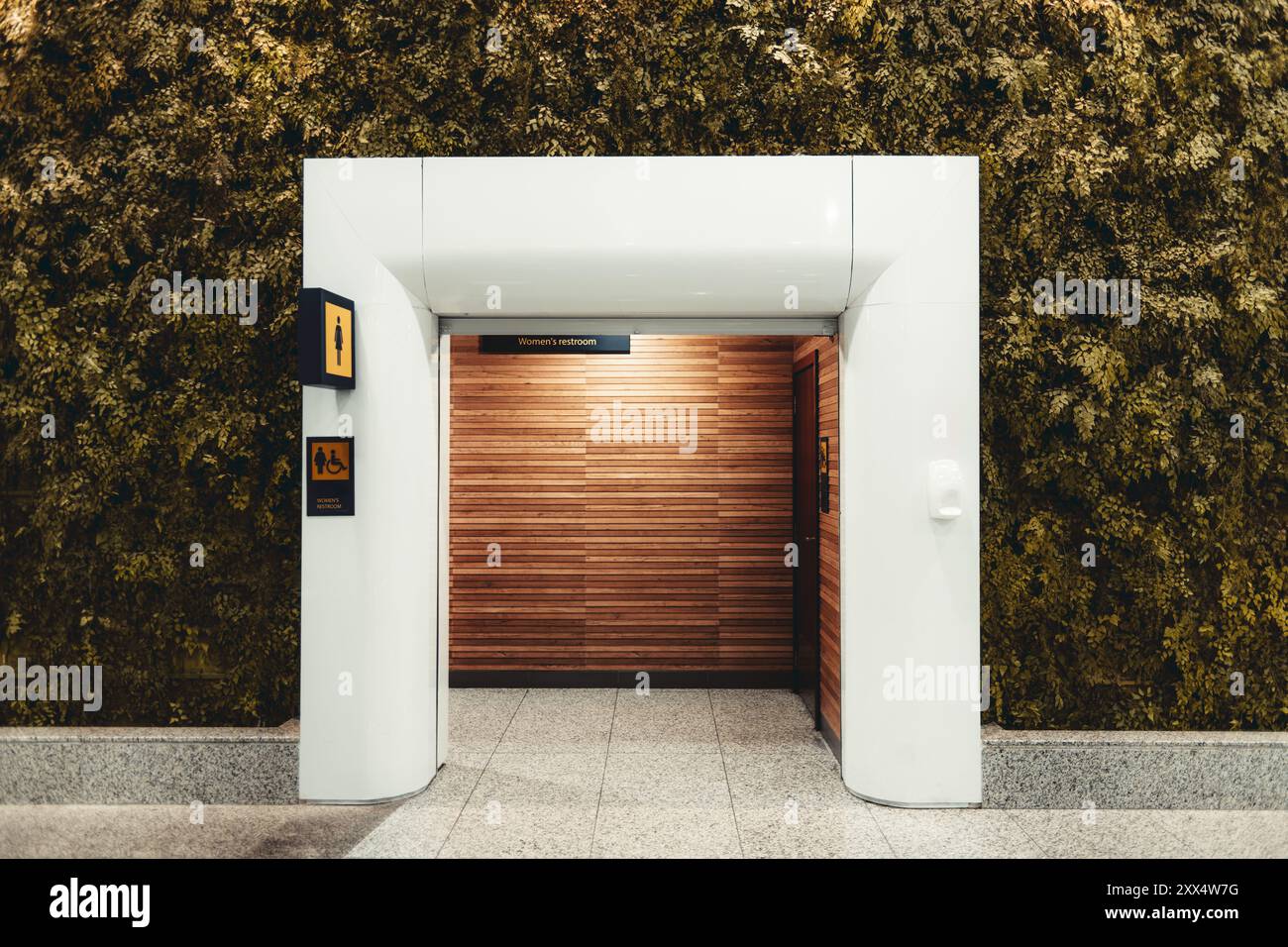 Entrance to a women's restroom with modern design, featuring a white ...