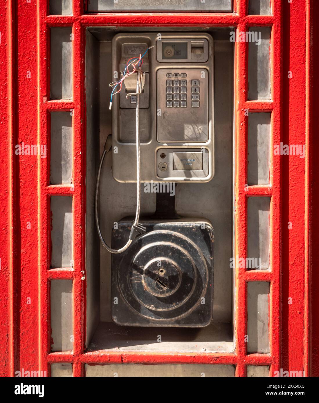 A vandalised public coin payphone set into the outside of a traditional ...