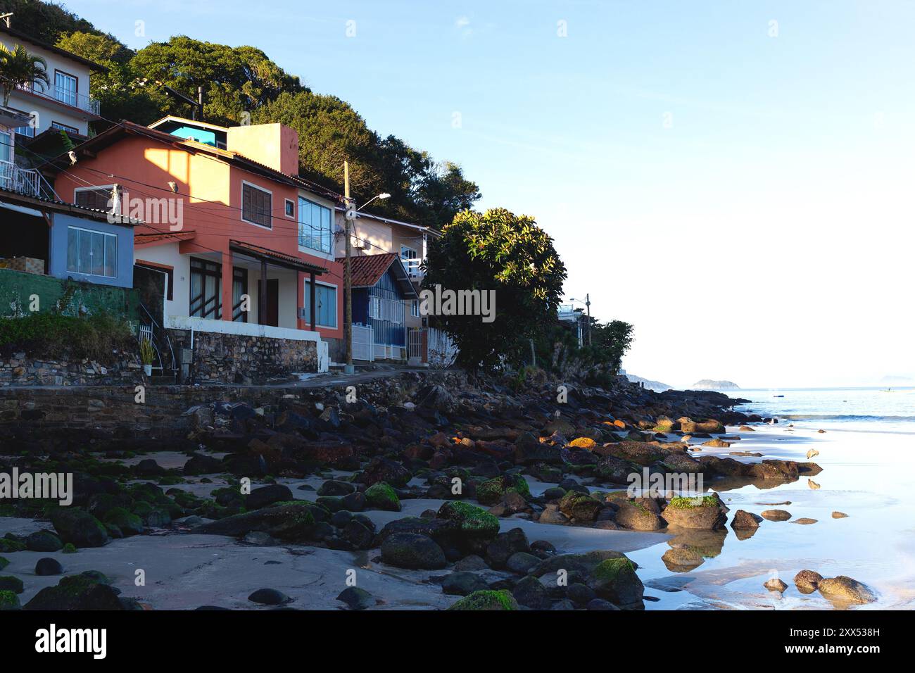 Colorful hillside village by the beach, surrounded by lush greenery and ...