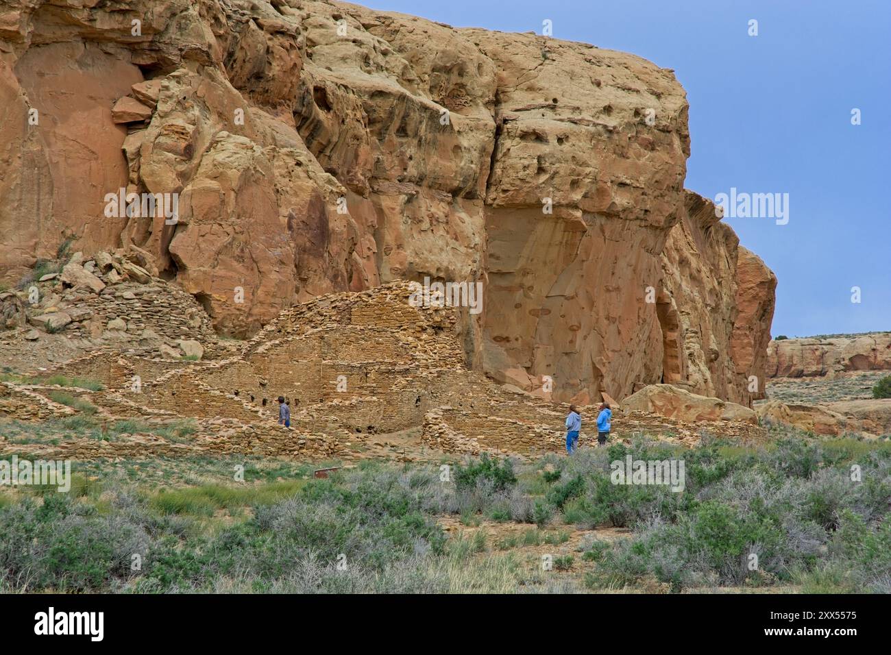 Tourists visiting the stone slab masonry ruins set against sandstone ...