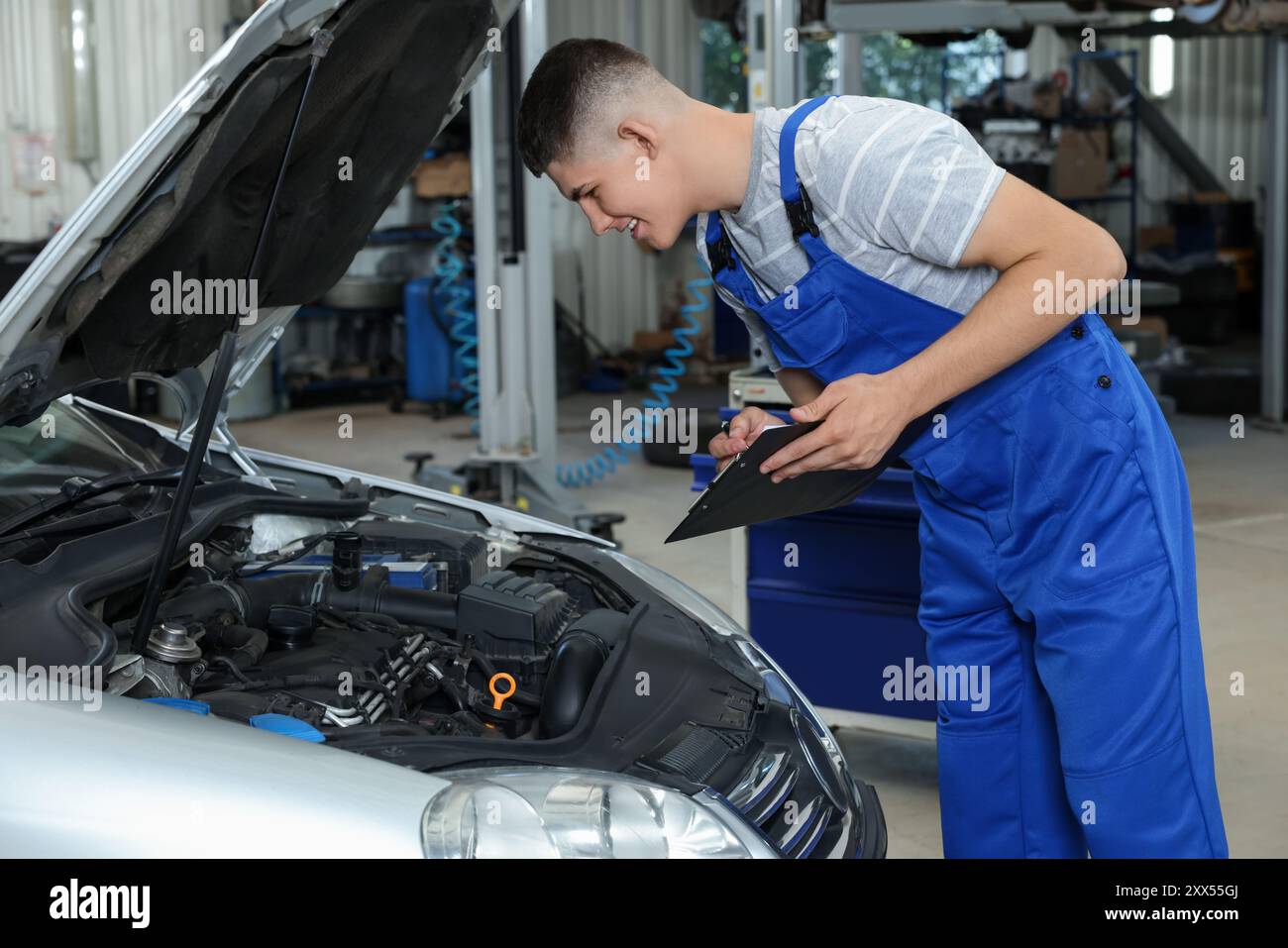 Young auto mechanic taking notes while doing car diagnostic at ...