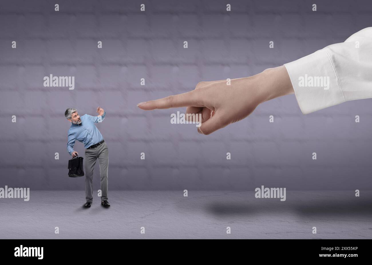 Big hand pointing at scared small businessman on grey background ...
