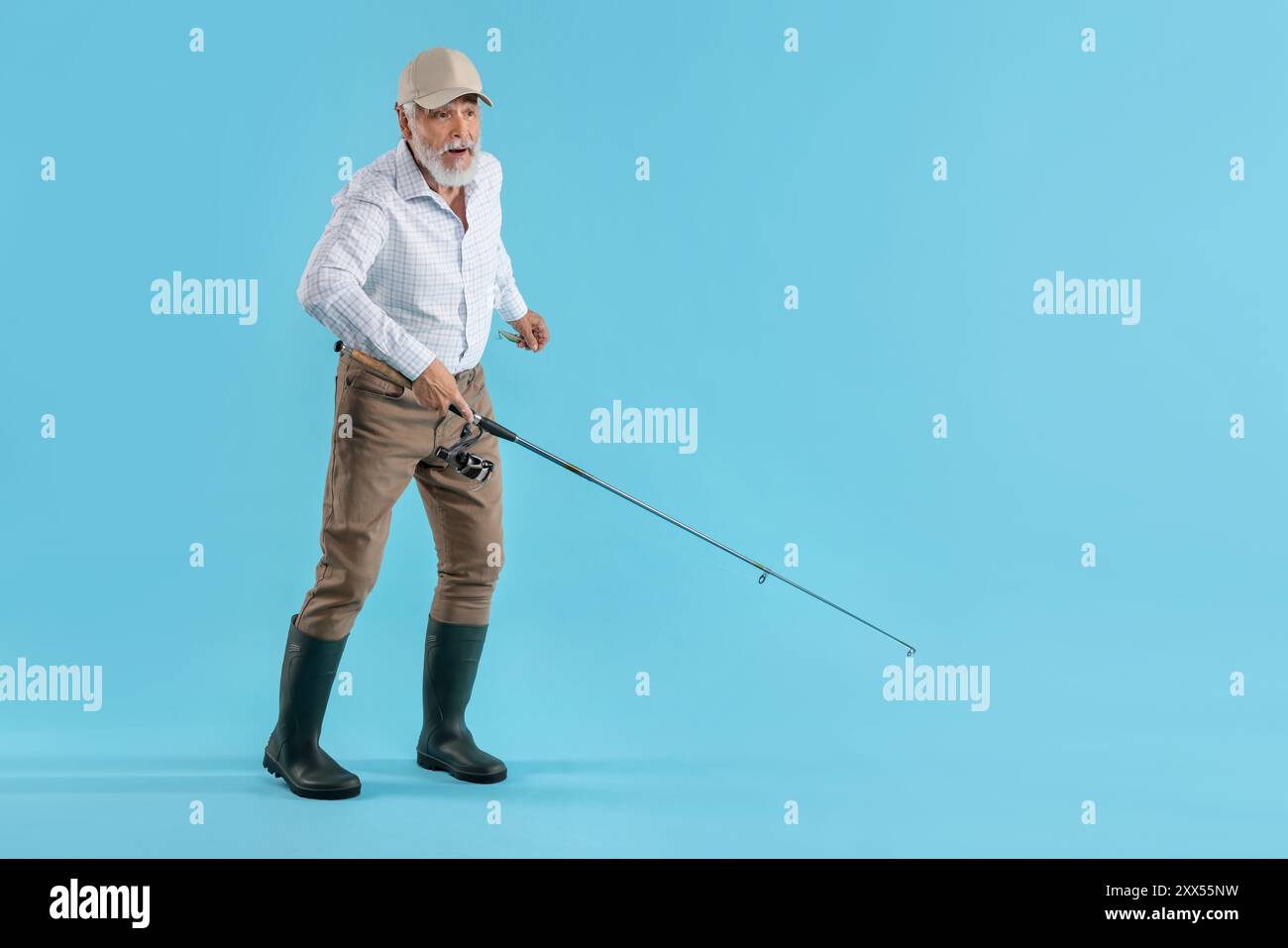 Fisherman with rod on light blue background Stock Photo - Alamy