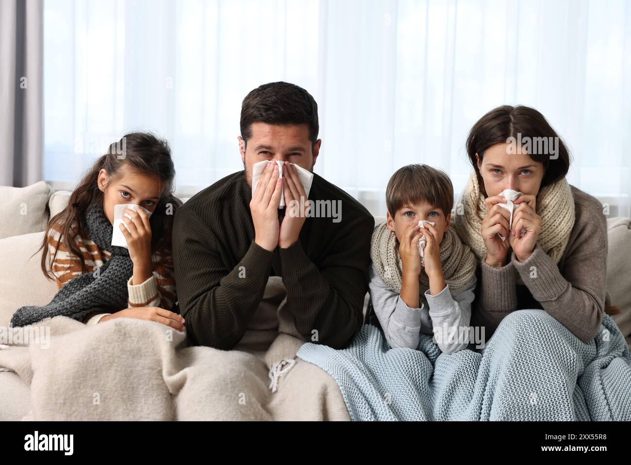 Cold symptom. Family suffering from fever on sofa at home Stock Photo ...