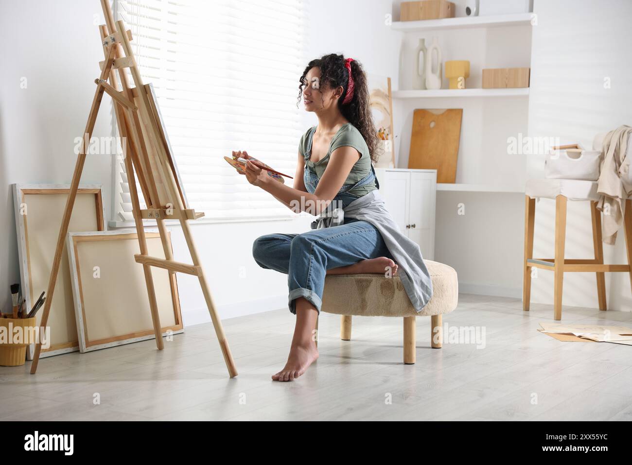 Beautiful woman drawing picture on canvas in studio Stock Photo - Alamy