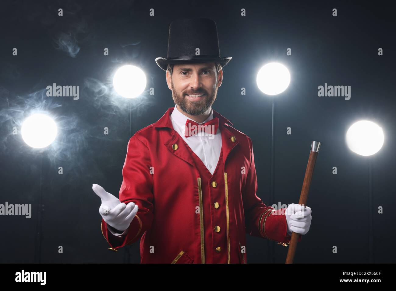 Portrait of showman in red costume, cane and hat on black background ...