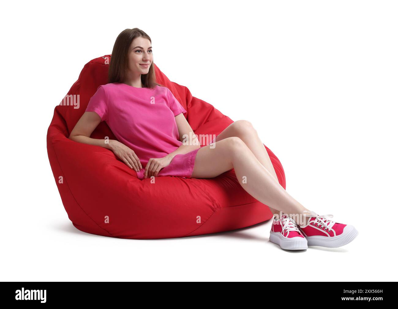 Beautiful young woman sitting on red bean bag chair against white ...