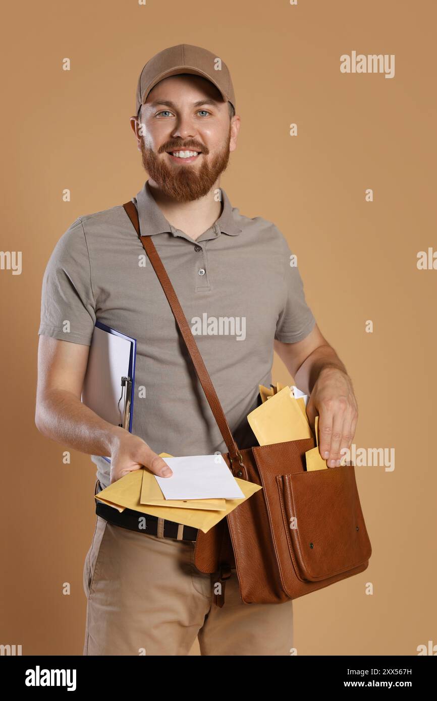 Happy young postman with leather bag delivering letters on brown ...