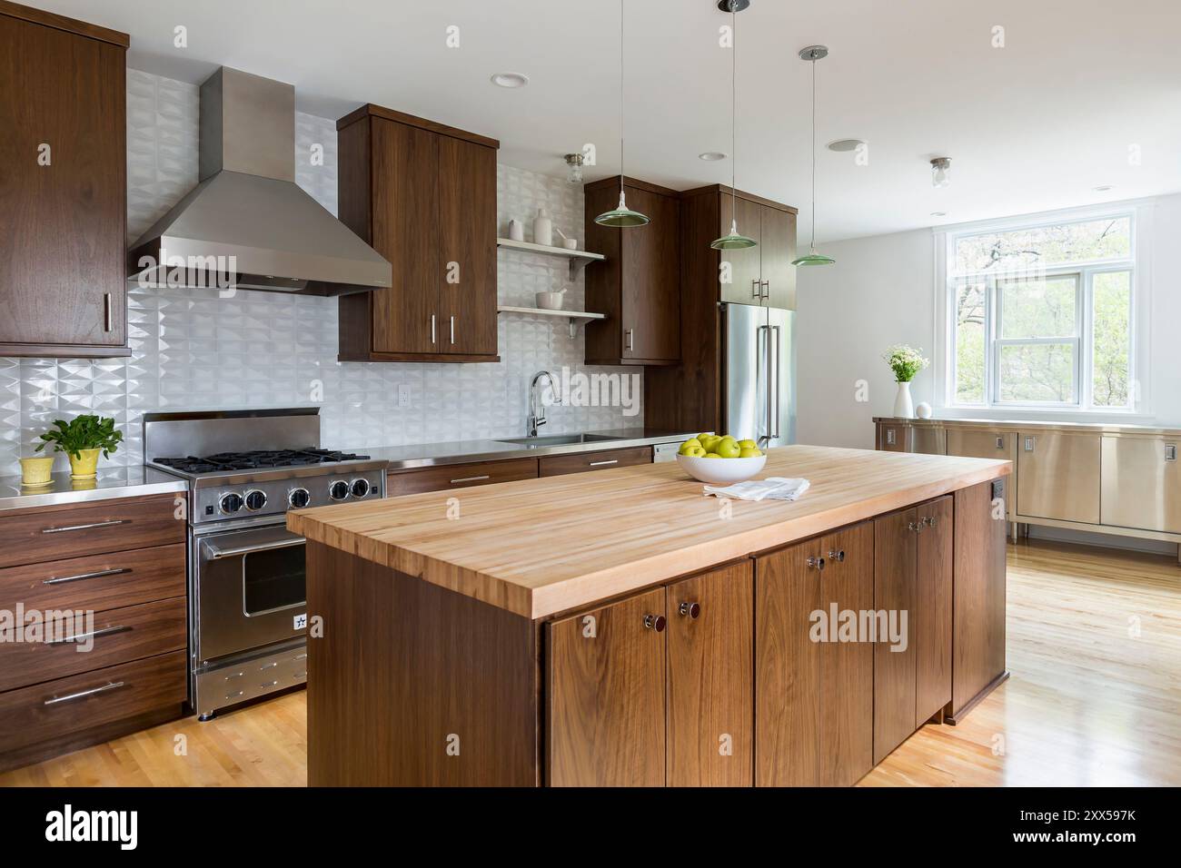 Large island in kitchen with walnut cabinets and white walls Stock ...