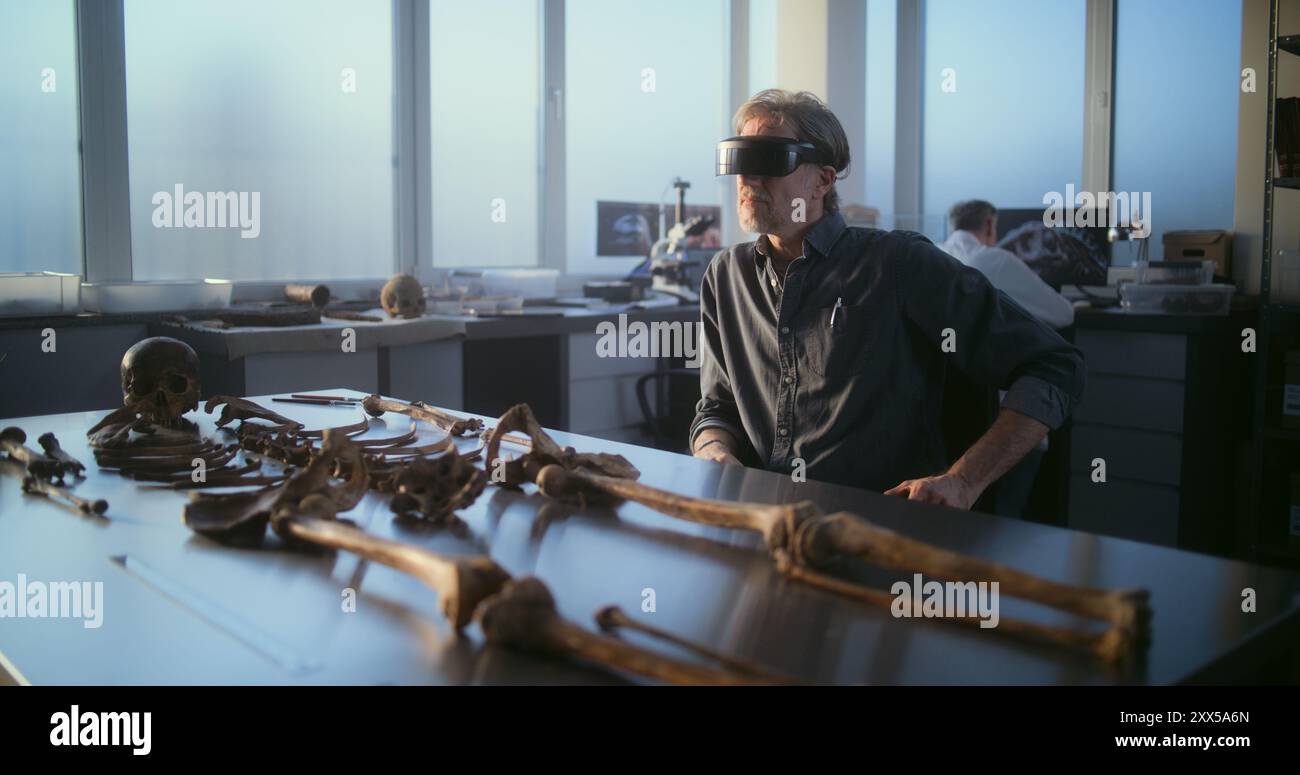 Mature archaeologist in VR headset studies remains of ancient extinct ...