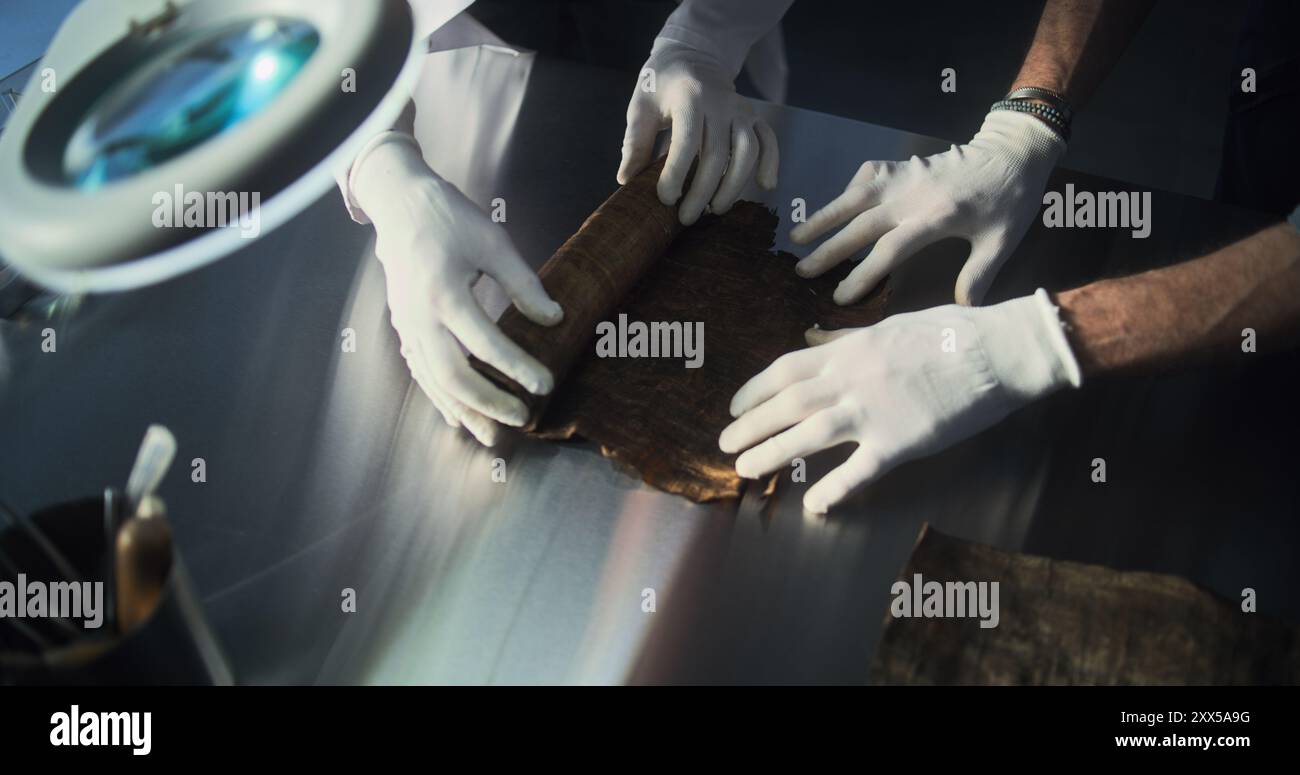 Two archaeologists in gloves carefully roll out ancient Egyptian ...