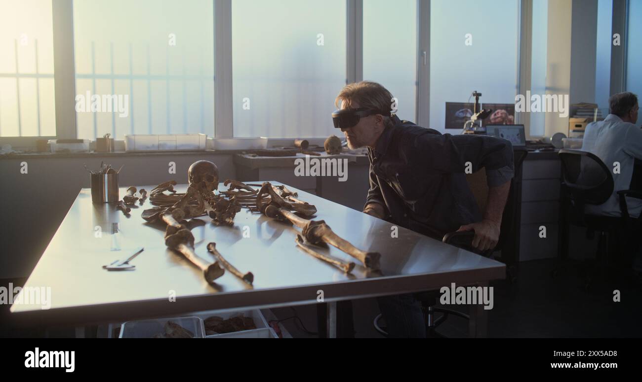 Mature archaeologist in AR headset studies remains of prehistoric human ...