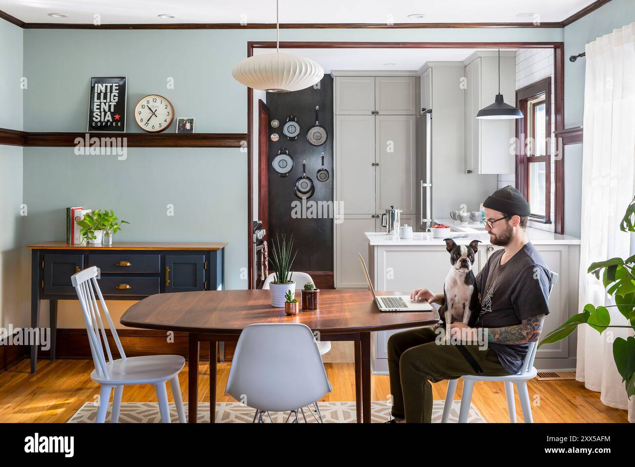 Dog sitting in man's lap in an updated dining room with view into ...