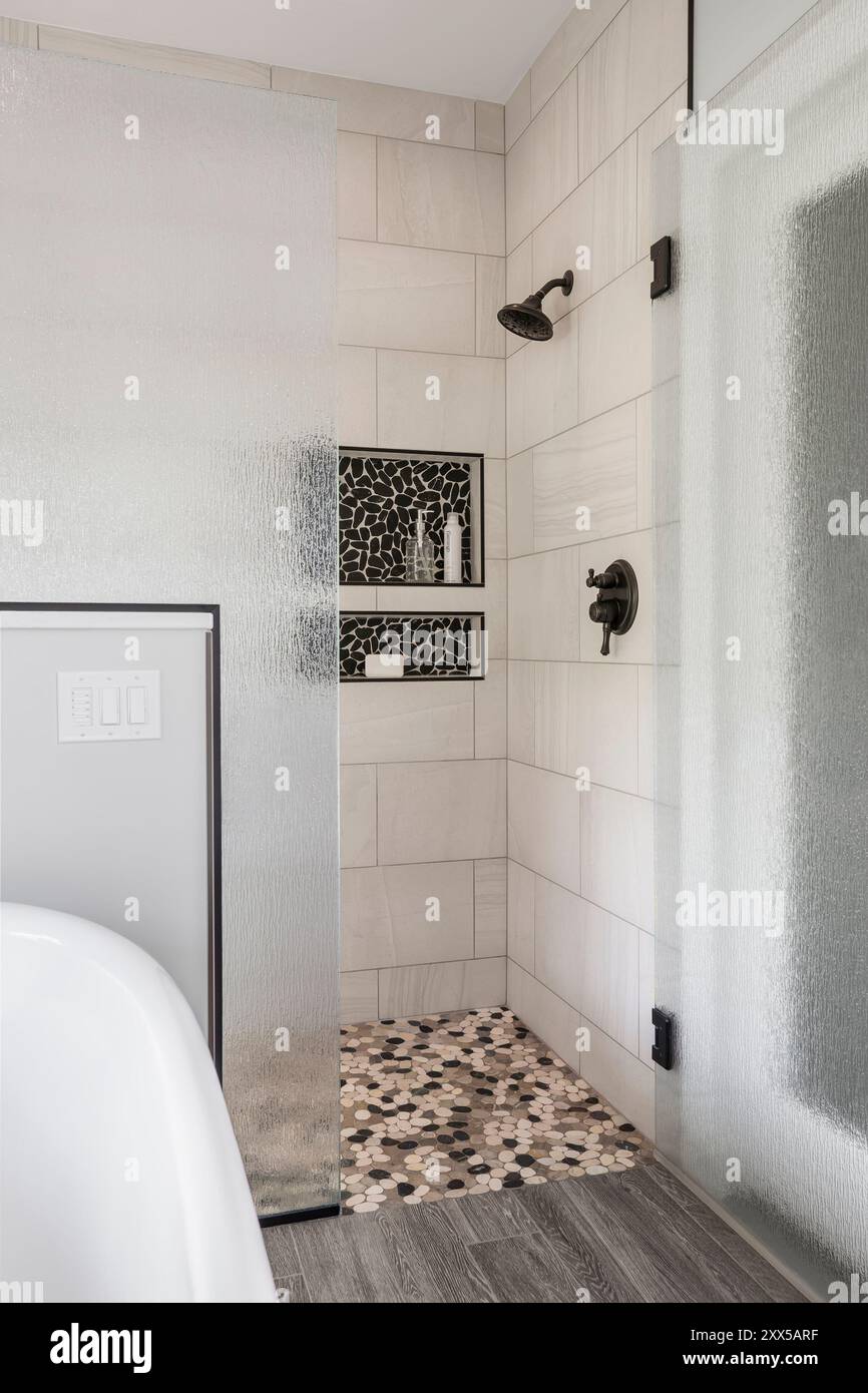 Large walk-in shower with pebble tile floor and shower niche Stock ...