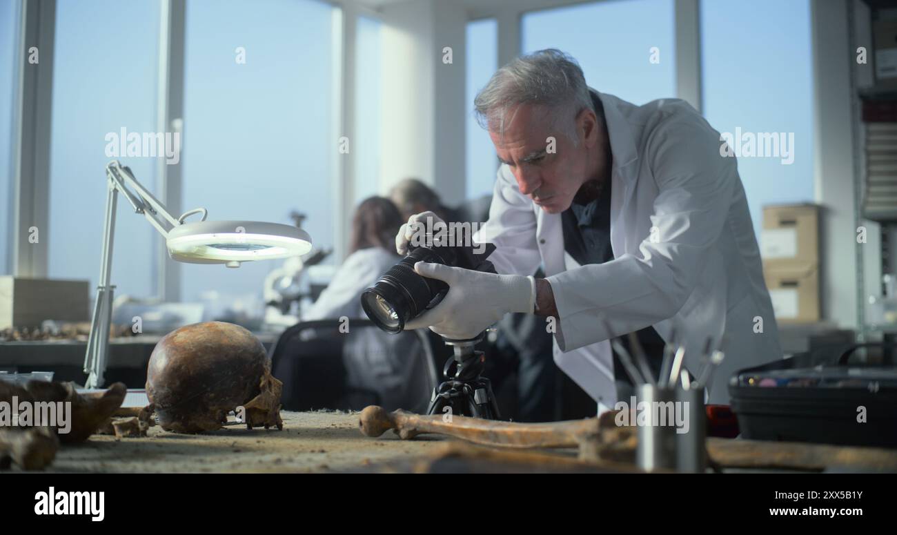 Senior archaeologist takes photo of fossil remains of prehistoric human skull and bones with ...