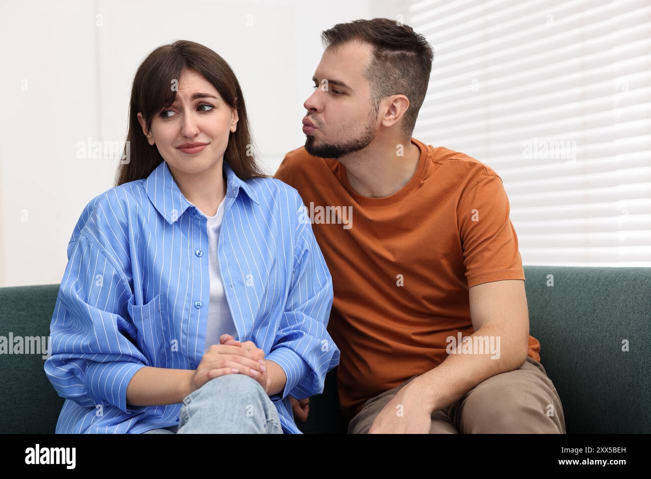 Man trying to kiss embarrassed woman at home Stock Photo - Alamy