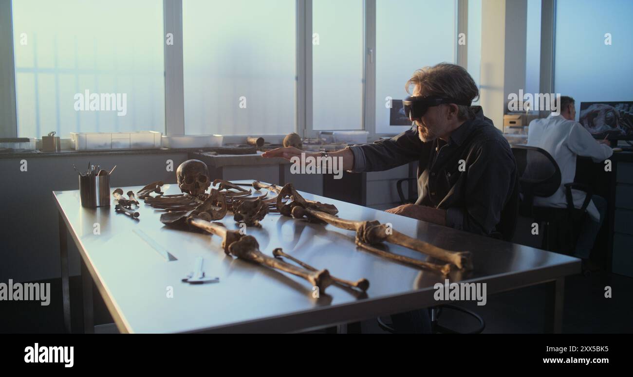 Mature archaeologist in AR headset studies remains of prehistoric human ...