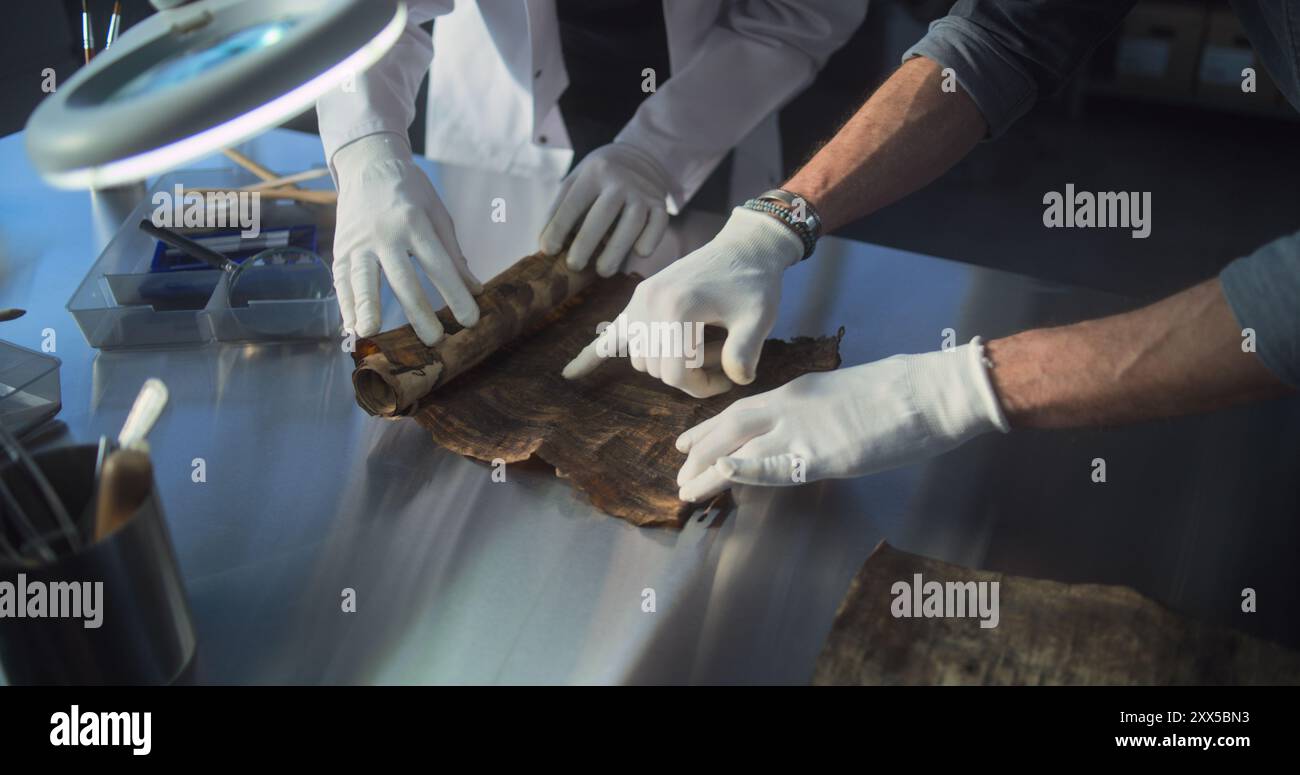 Two archaeologists in gloves carefully roll out ancient Egyptian ...