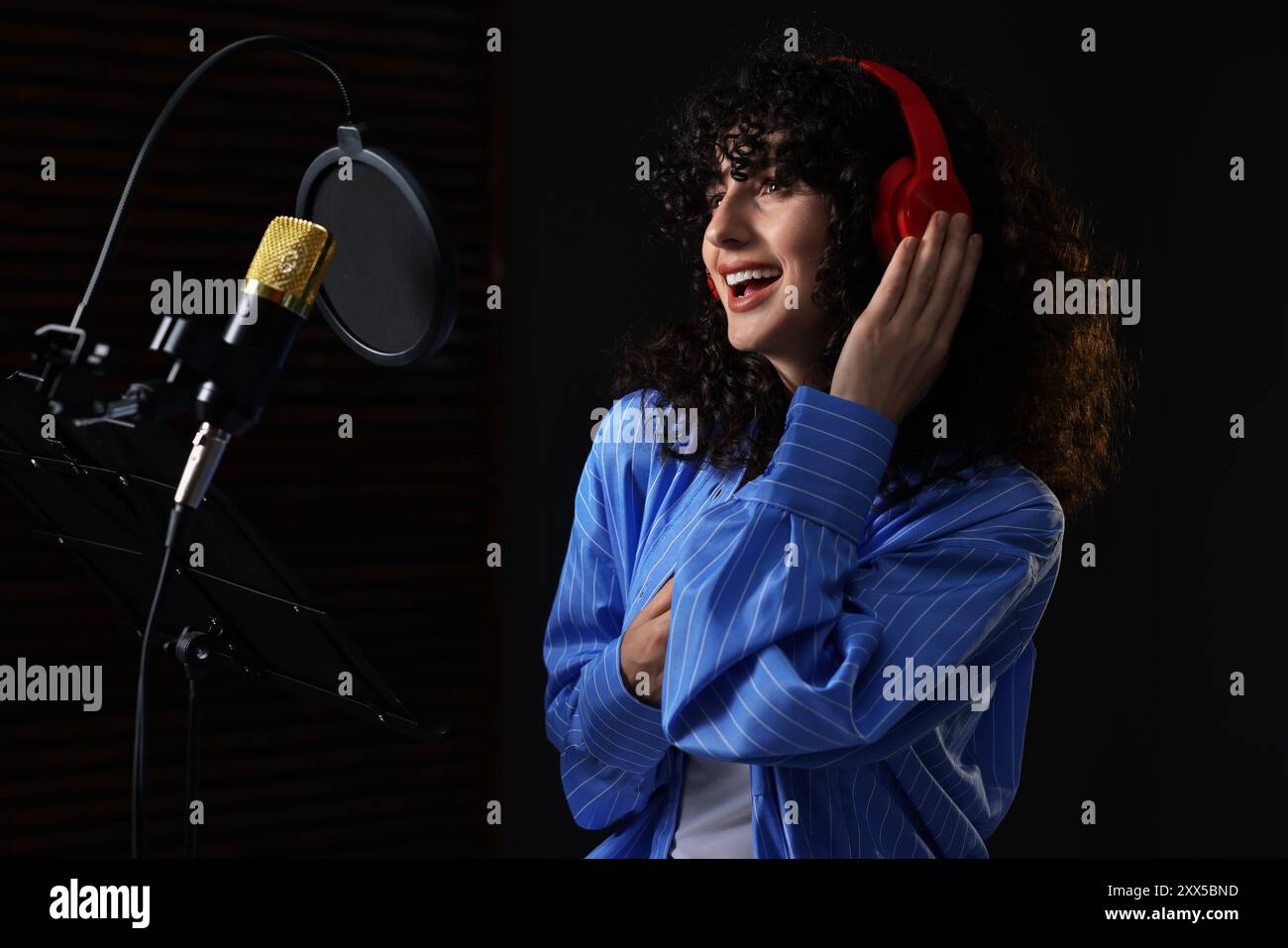 Vocalist with headphones singing into microphone in professional record ...