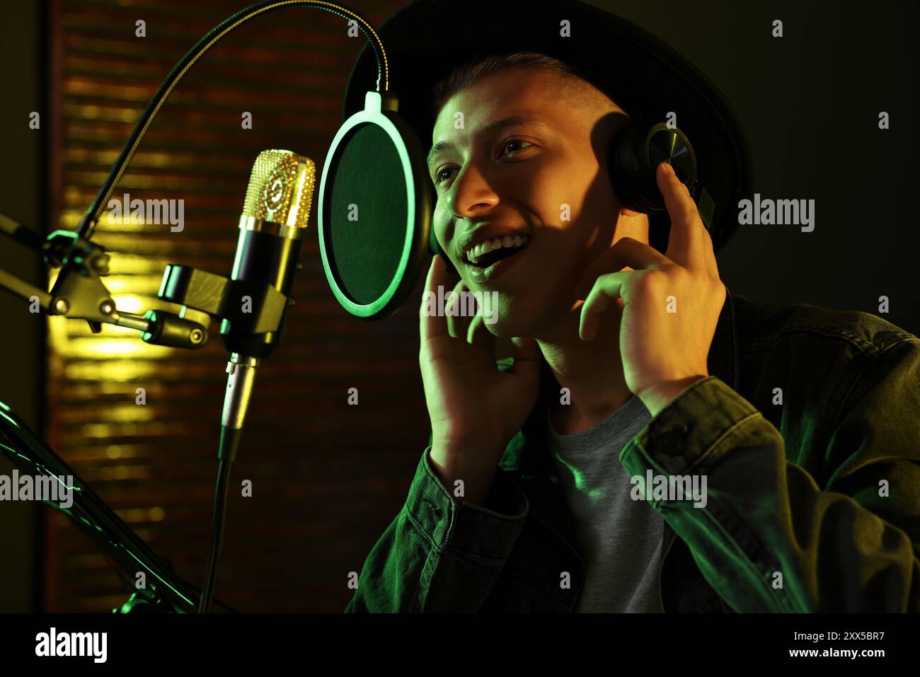 Vocalist with headphones singing into microphone in professional record ...