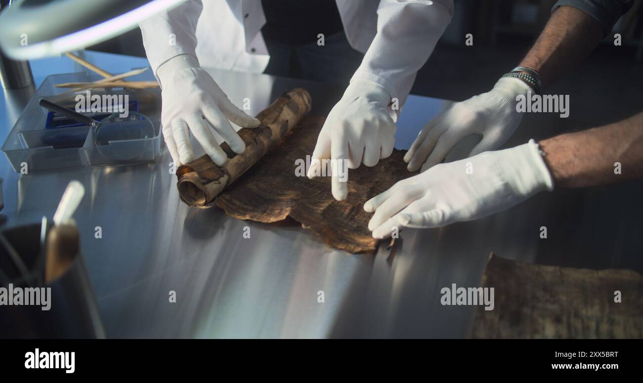 Two archaeologists in gloves carefully roll out ancient Egyptian ...
