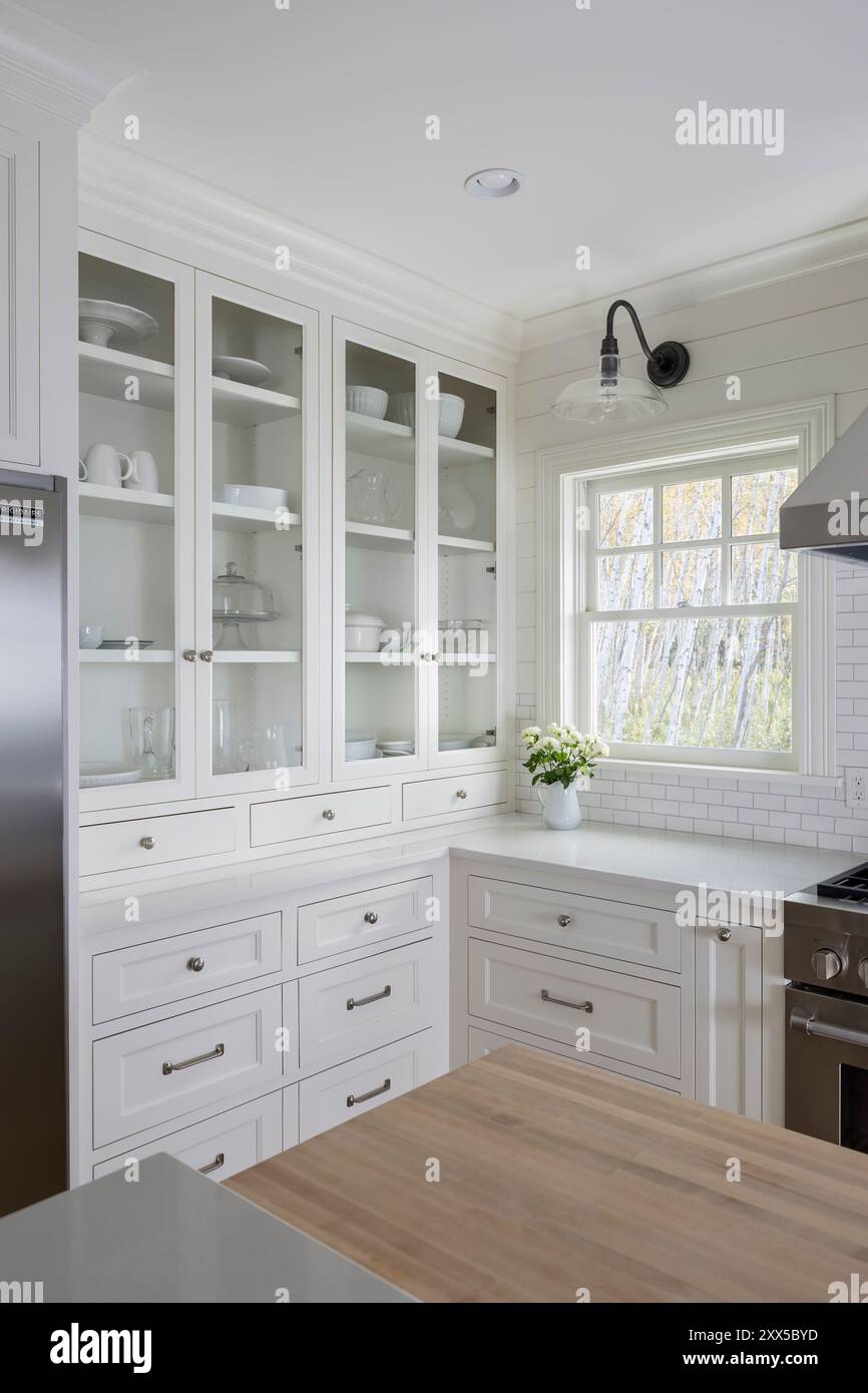 Corner of white kitchen showing dishes on display behind glass cabinets ...