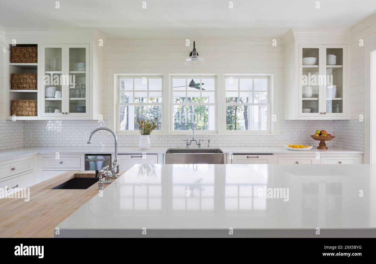 White kitchen with two sinks and lower level butcher block counter area ...