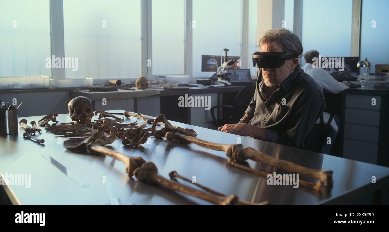 Mature archaeologist in VR headset studies remains of ancient human ...