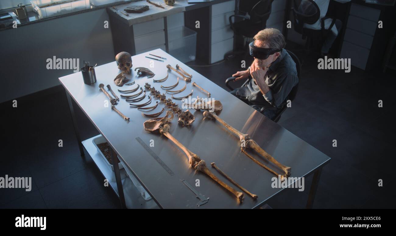 Mature archaeologist in VR headset studies remains of ancient extinct ...