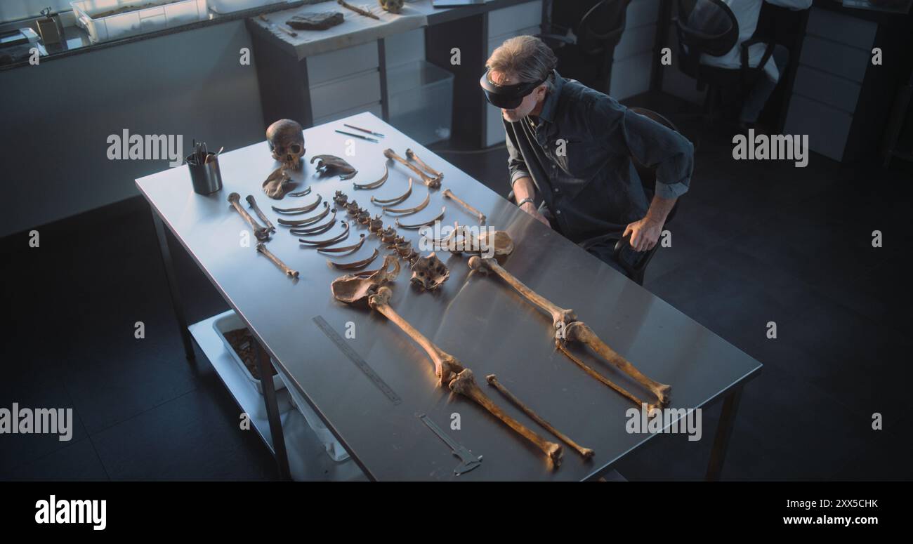 Mature archaeologist in VR headset studies remains of ancient extinct ...