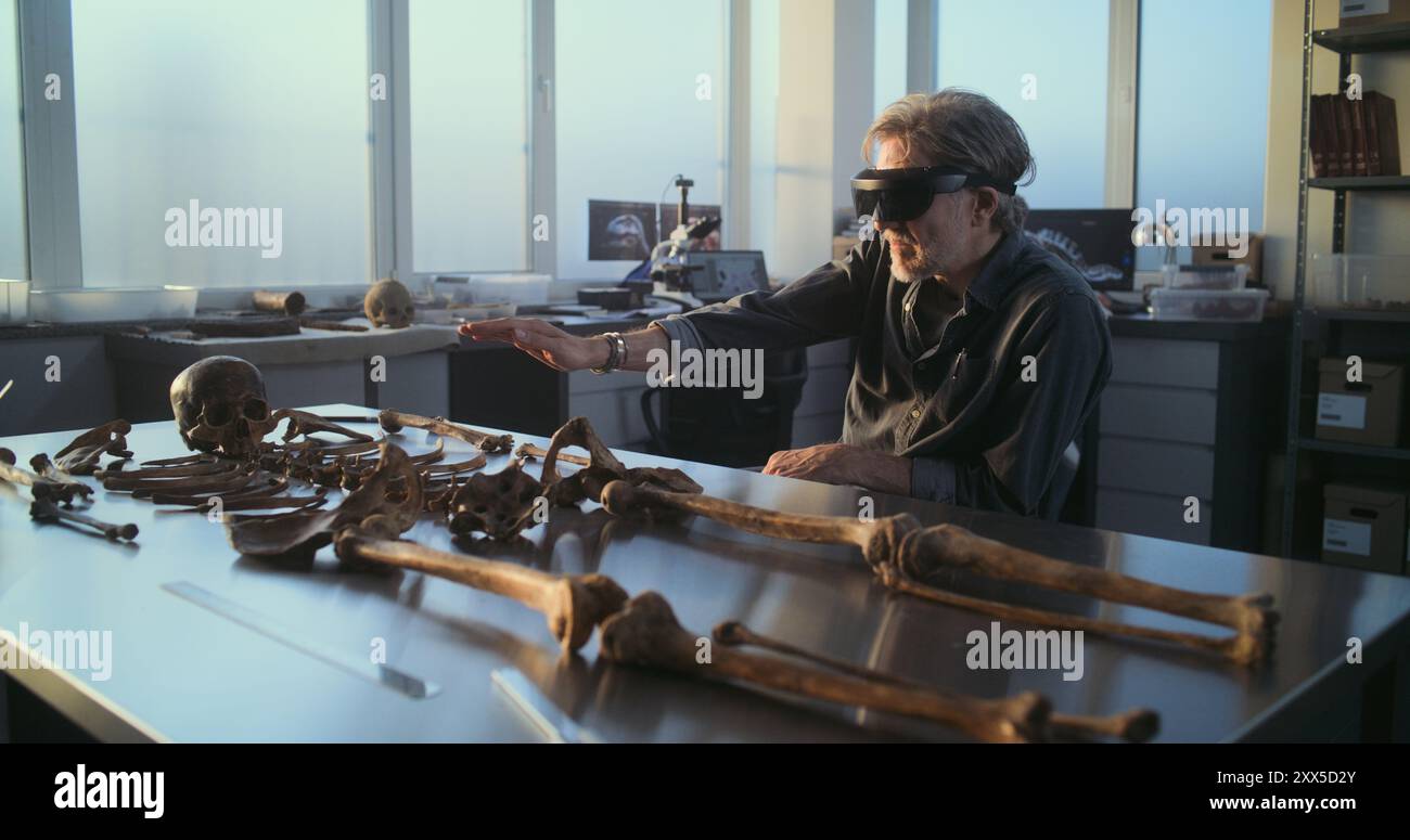 Mature archaeologist in VR headset studies remains of ancient human ...