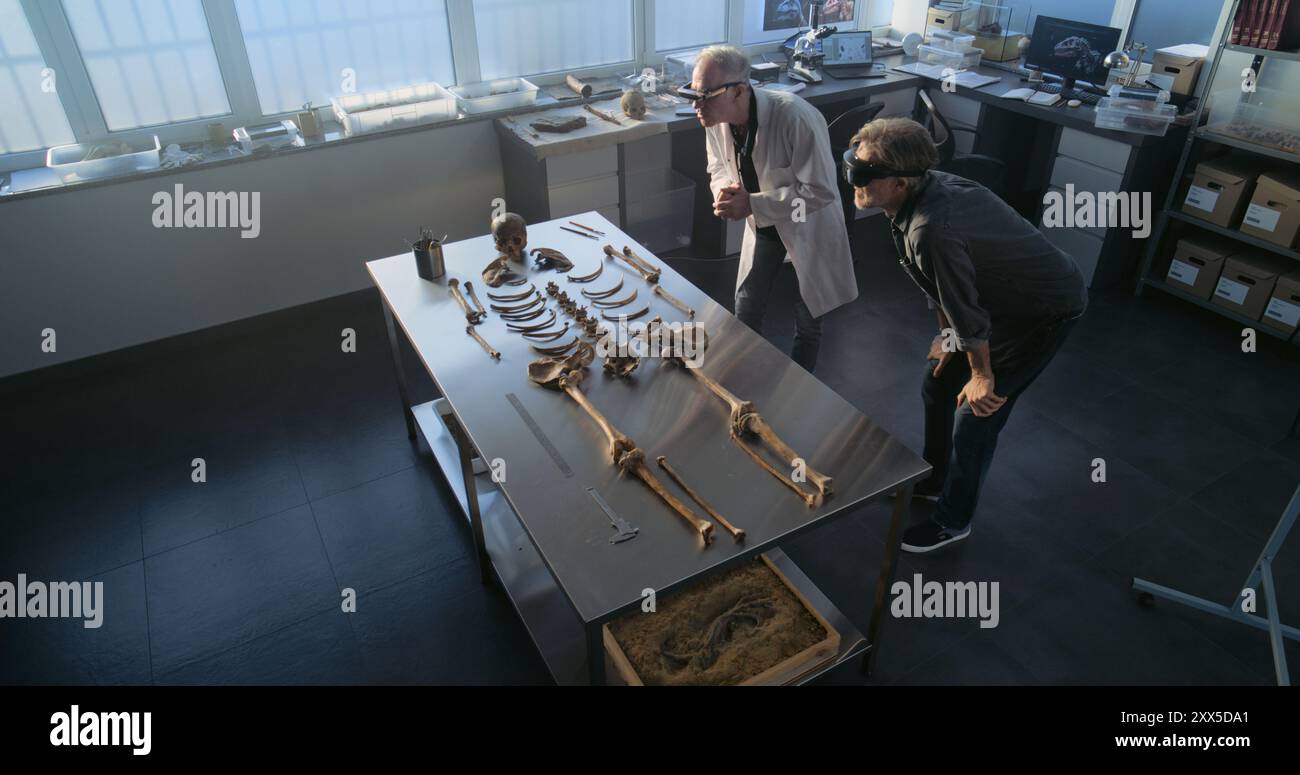 Two archaeologists in VR headsets study remains of ancient extinct ...
