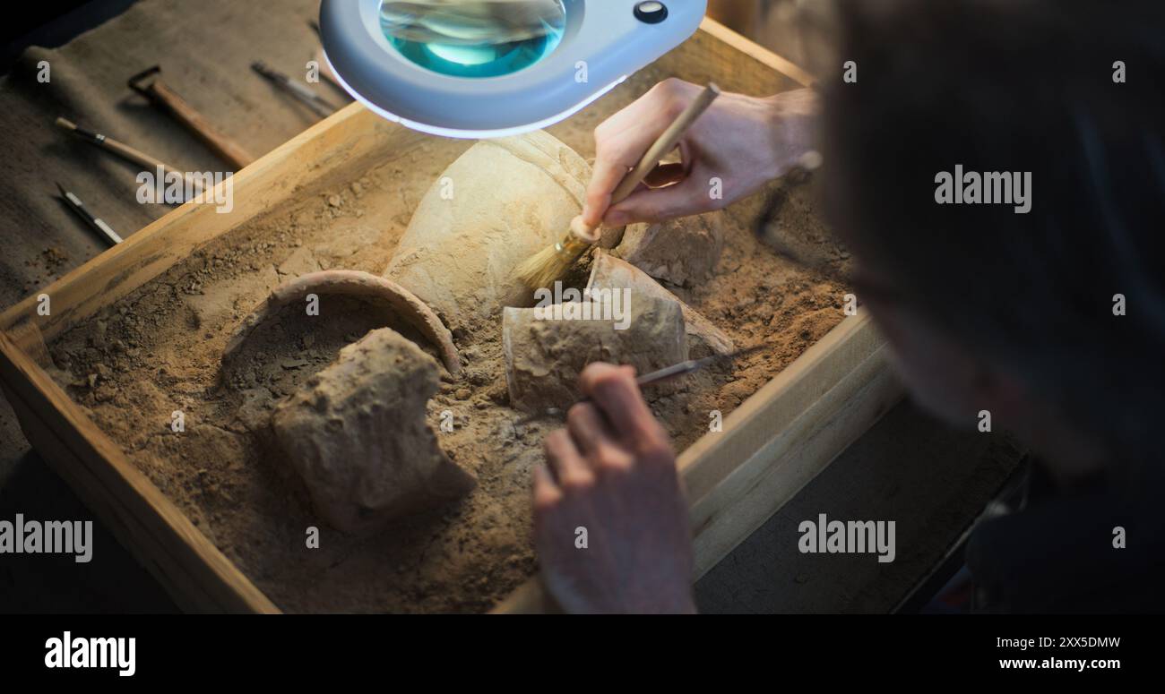 Close up of mature archaeologist cleaning cultural heritage of extinct civilization from sand ...
